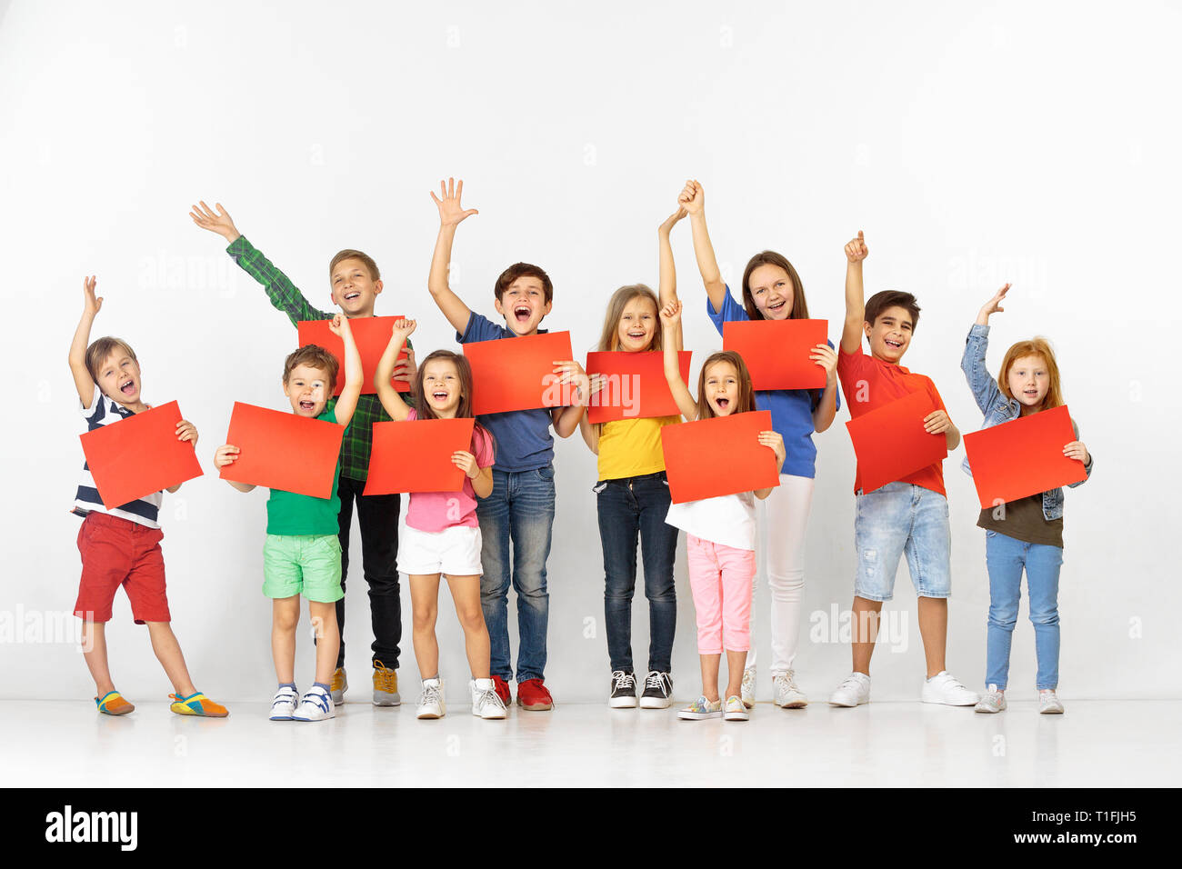 Group of happy screaming children with a red empty banners isolated in ...