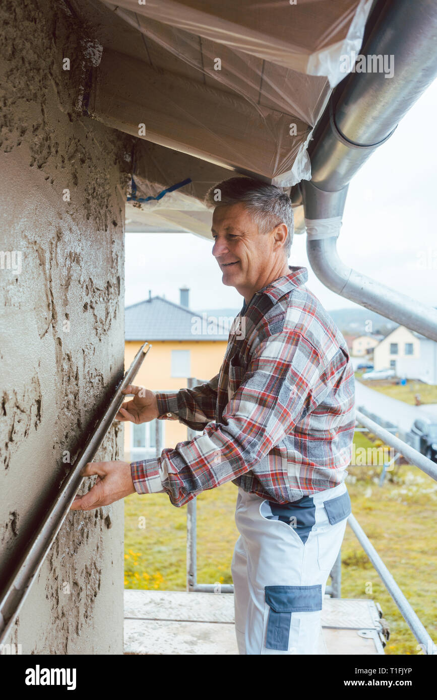 Plasterer smoothing plaster on a facade Stock Photo - Alamy