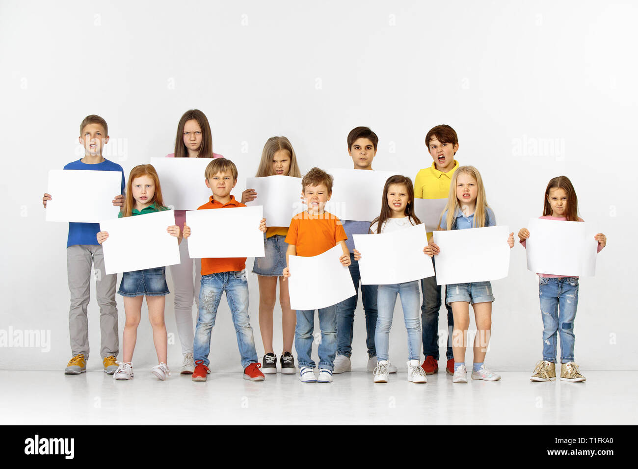 Group of angry children with a white empty banners isolated in studio ...