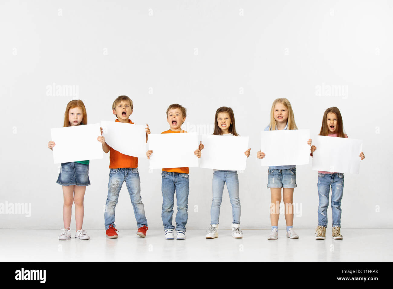 Group of angry screaming children with a white empty banners isolated ...