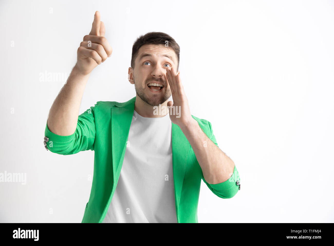 Happy business man standing, smiling and pointing up isolated on gray ...