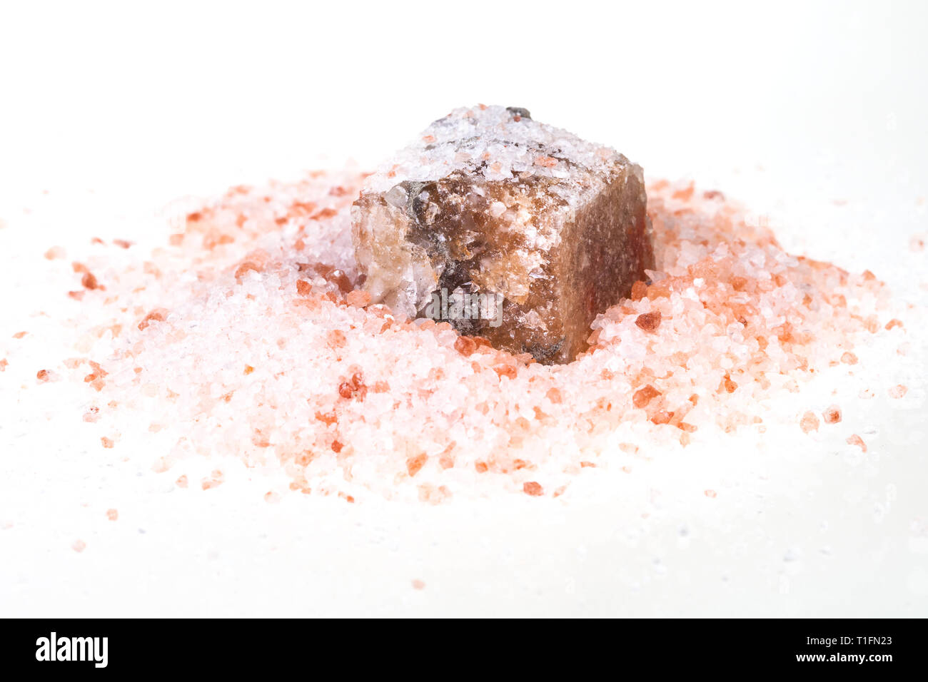 raw Halite mineral in pile of grained pink Himalayan Salt on white ...