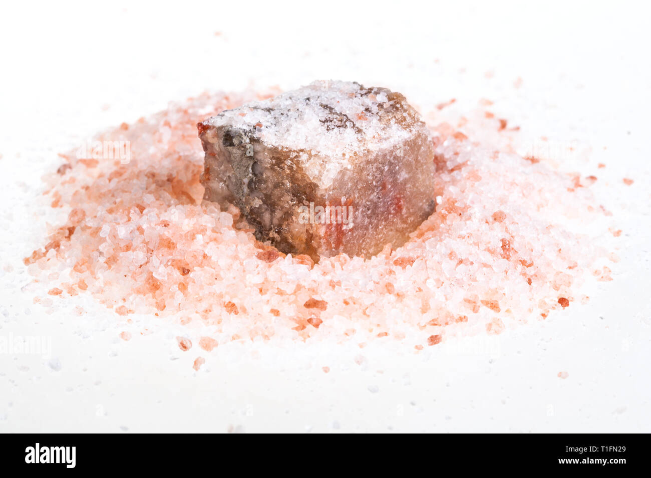 natural Halite mineral in pile of grained pink Himalayan Salt on white ...