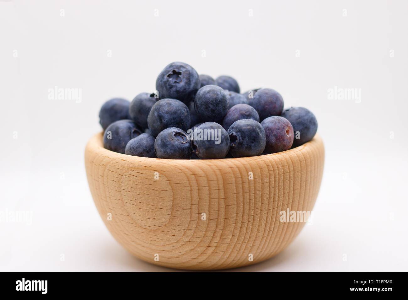 Side view of wooden bowl full of blueberries isolated on white ...