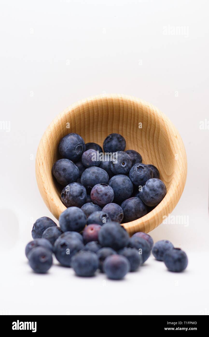 Overturned wooden bowl of fresh blueberries isolated on white ...