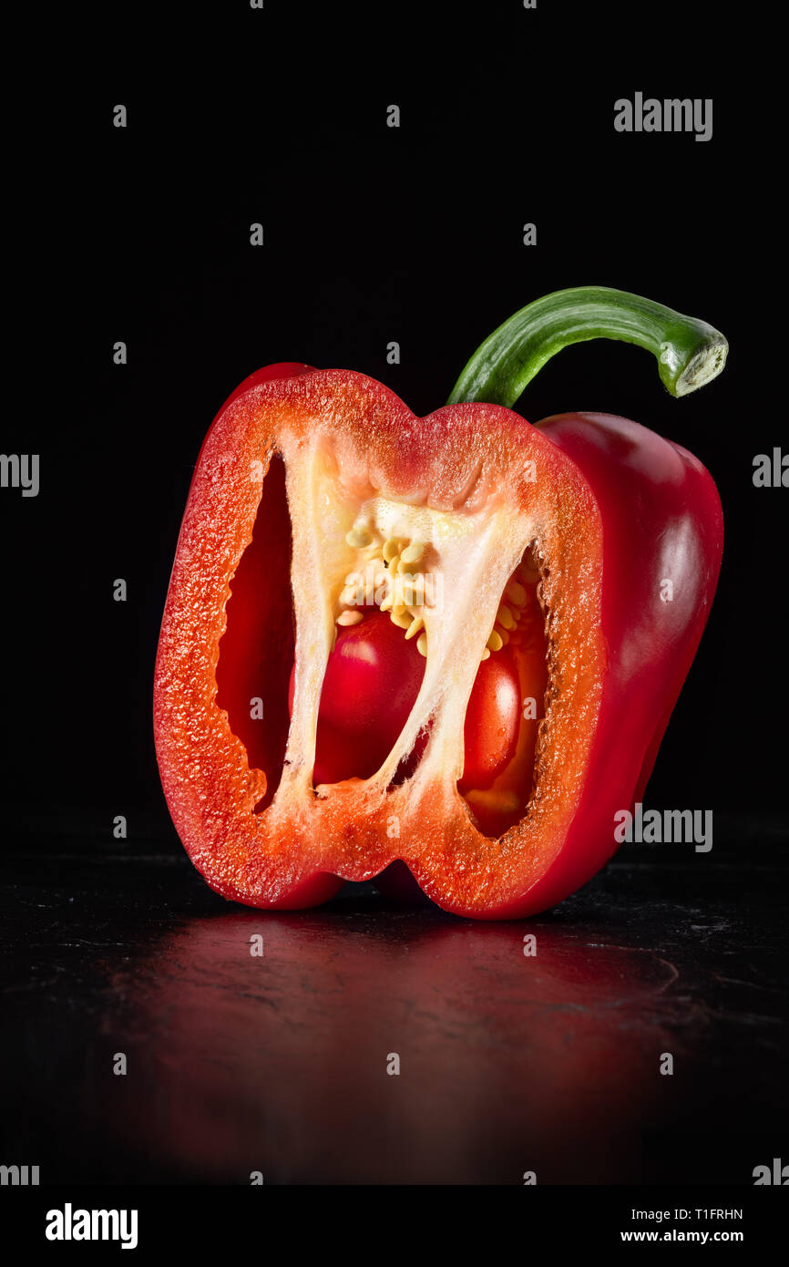 Food photo of a cut red pepper on a black slate plate exposing the ...