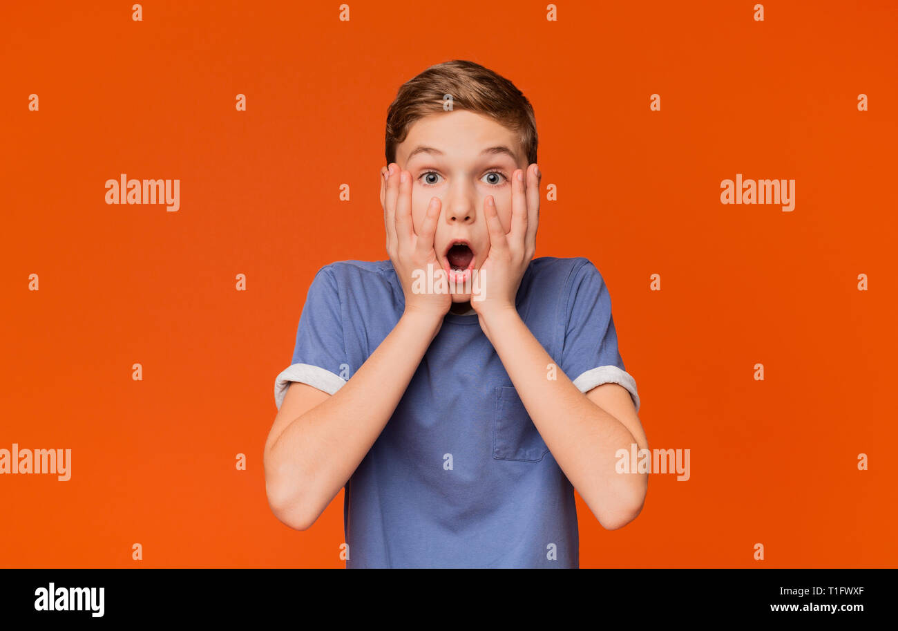 Shocked kid keeping mouth open and touching face Stock Photo - Alamy