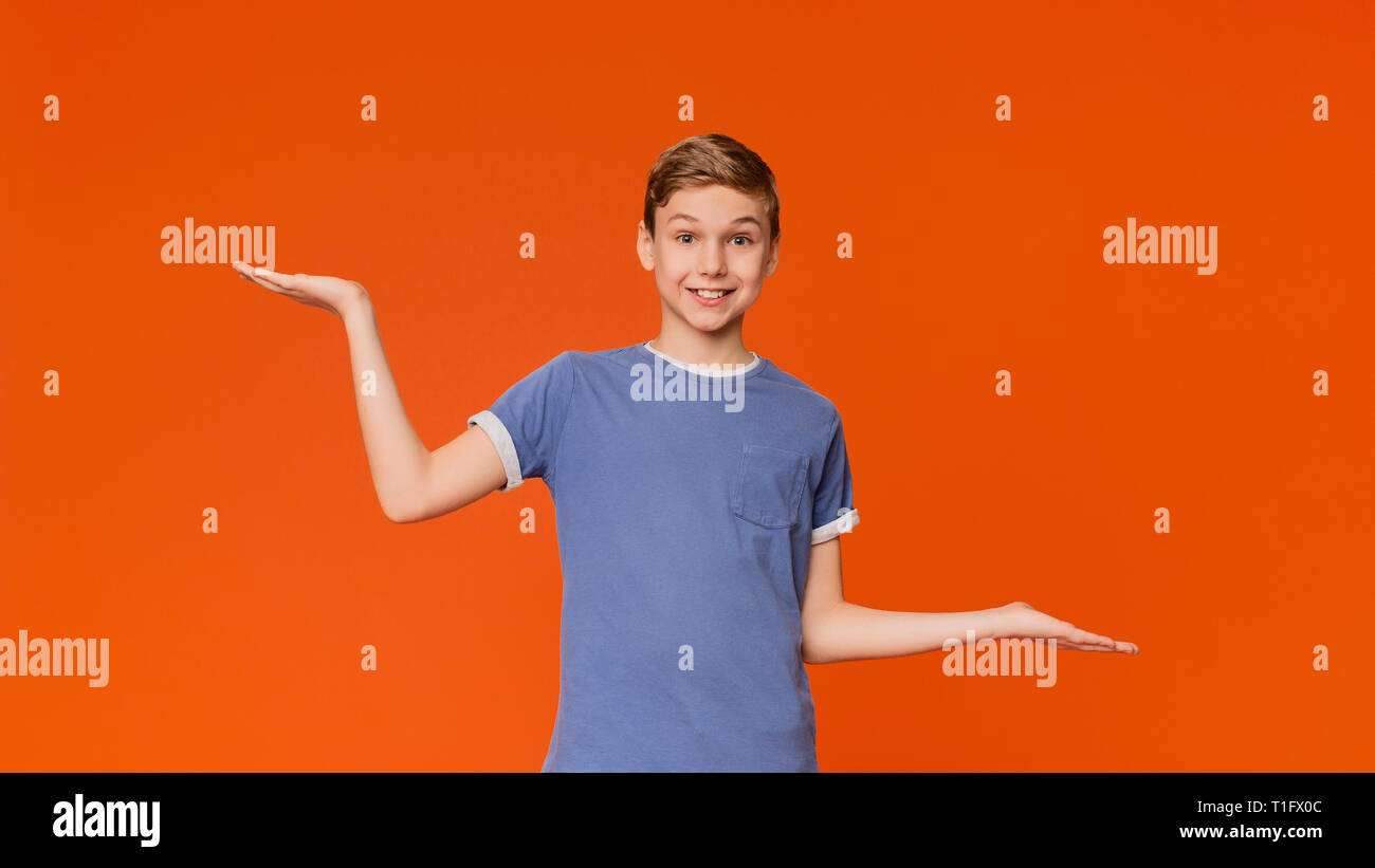Hesitant boy spreading hands sideway with empty space Stock Photo - Alamy