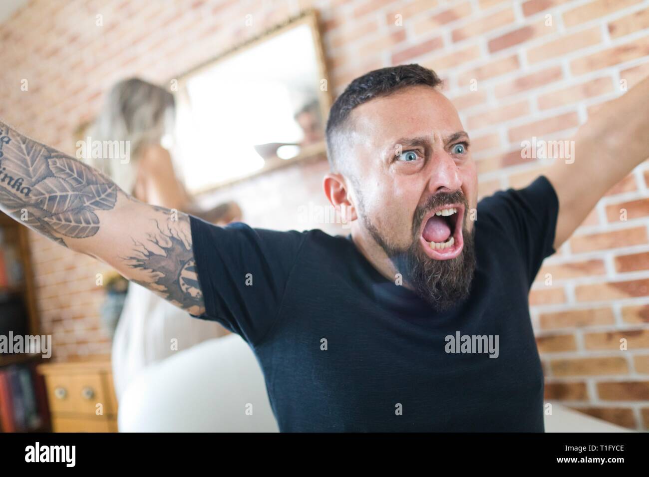 Man watching television and woman is arguing in background ...
