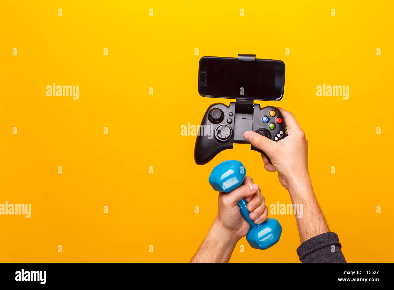 Photo of man's hand with dumbbell and game console with smartphone ...