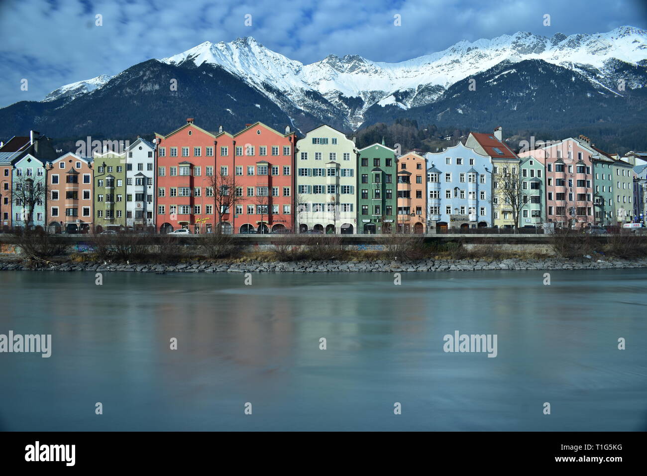 The Austrian alps behind the river "Inn" and Colorful houses. This ...