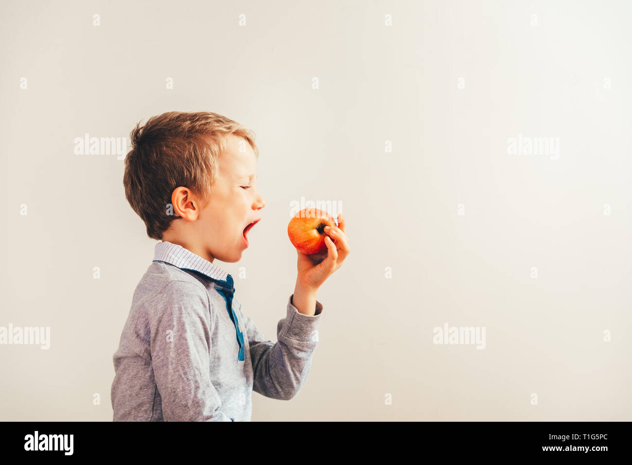 Child ready to eat an apple at a bite, isolated on white background ...