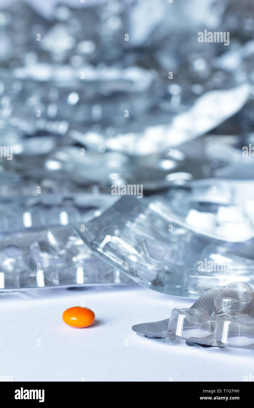 One single pill in front of many empty blister packages on white ...