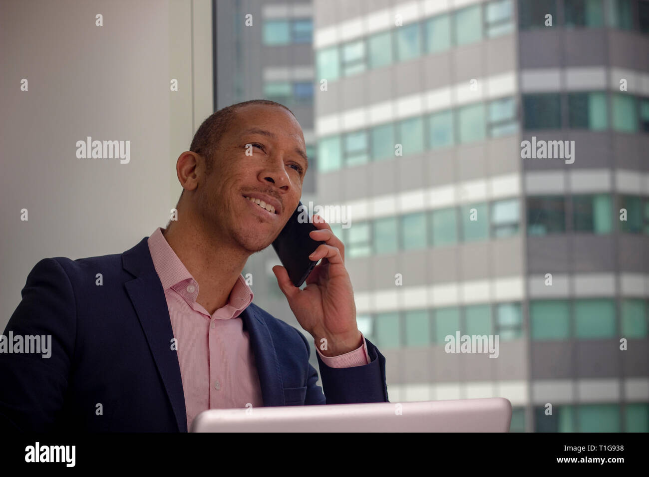 Happy office worker making a phone call at his computer Stock Photo - Alamy