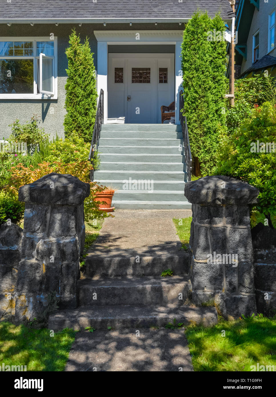 Concrete pathway to residential house entrance via landscaped front ...