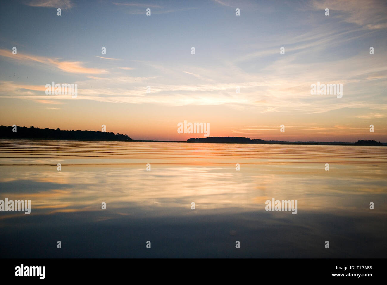 Sun setting over water Stock Photo - Alamy