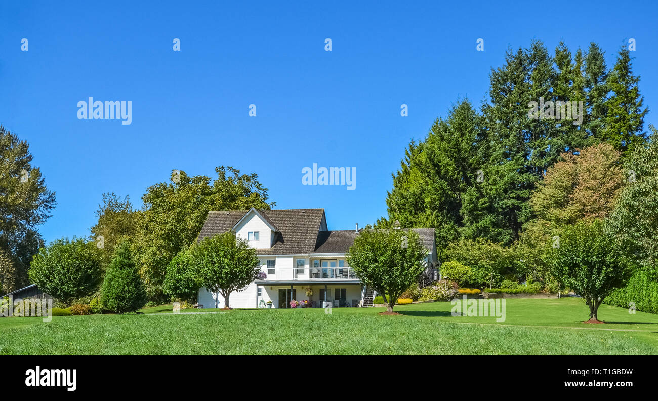 Big family house on a farm with huge green lawn in front on sunny day ...