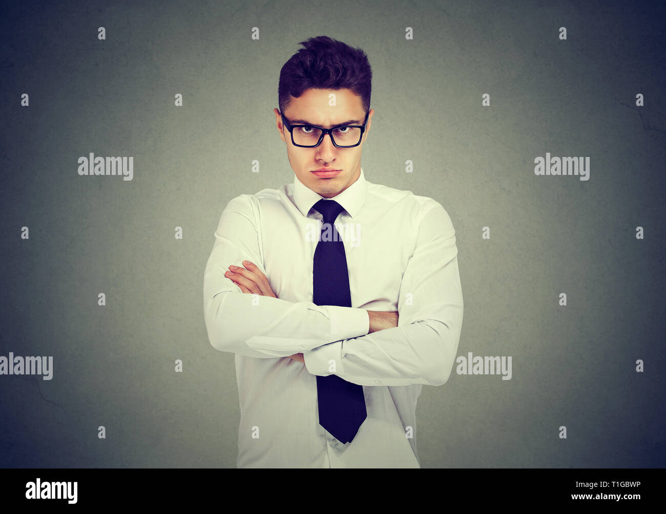 Frowning angry business man looking at camera on gray wall background ... Frowning angry business man looking at camera on gray wall background ...