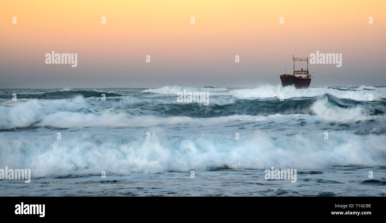 Abandoned ship in the stormy sea with big wind waves during sunset ...