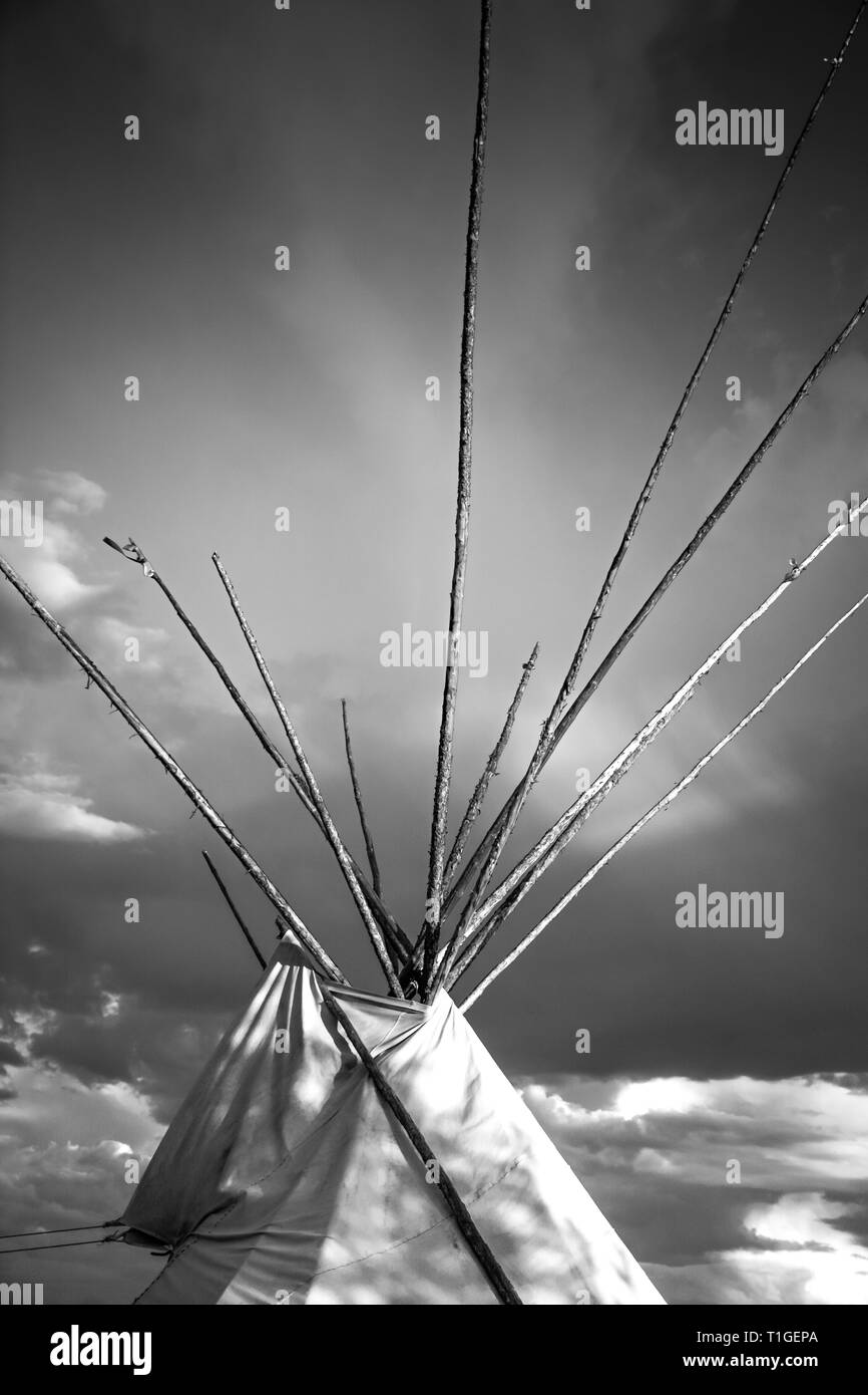 A cropped close up view in black and white of the top of a tipi with ...