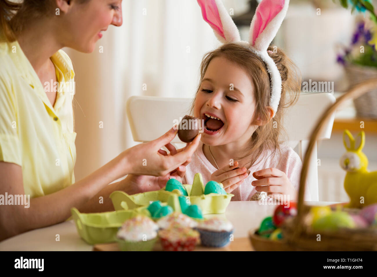 Mother and daughter celebrating Easter, eating chocolate eggs. Happy ...