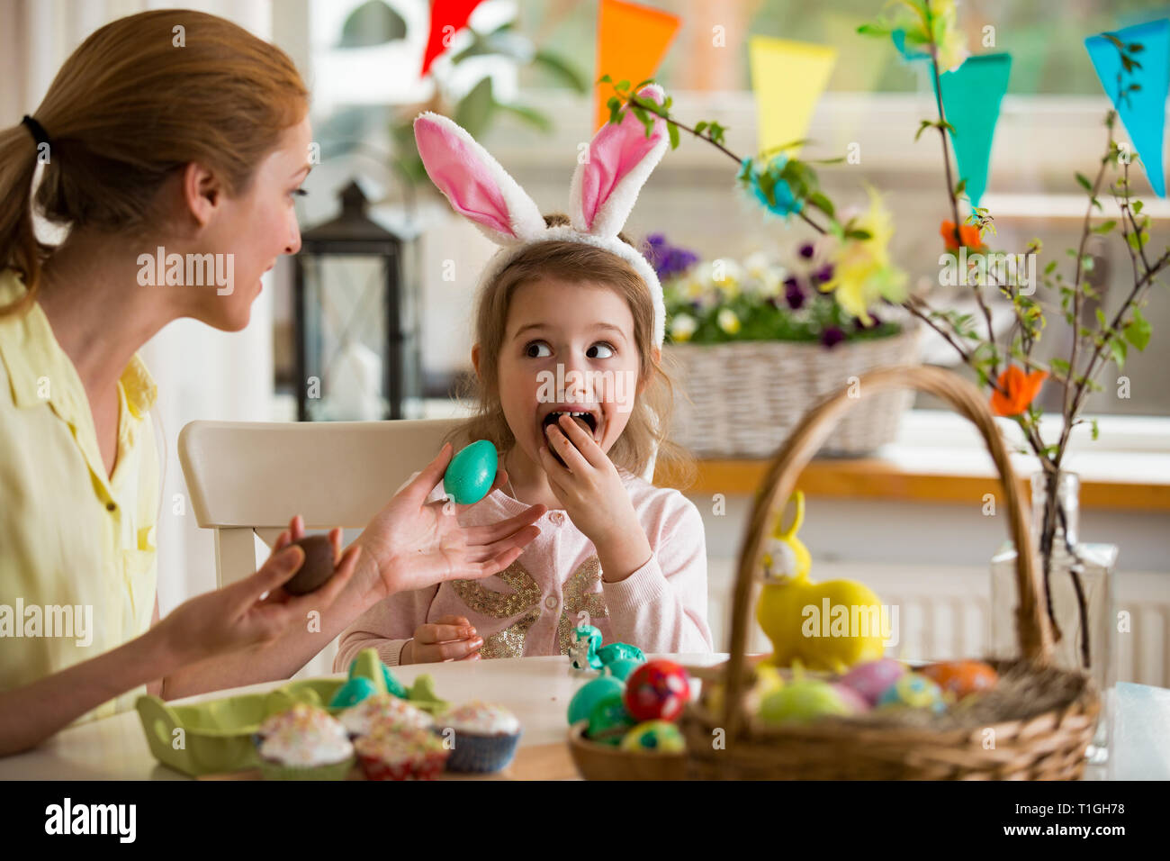 Mother and daughter celebrating Easter, eating chocolate eggs. Happy ...
