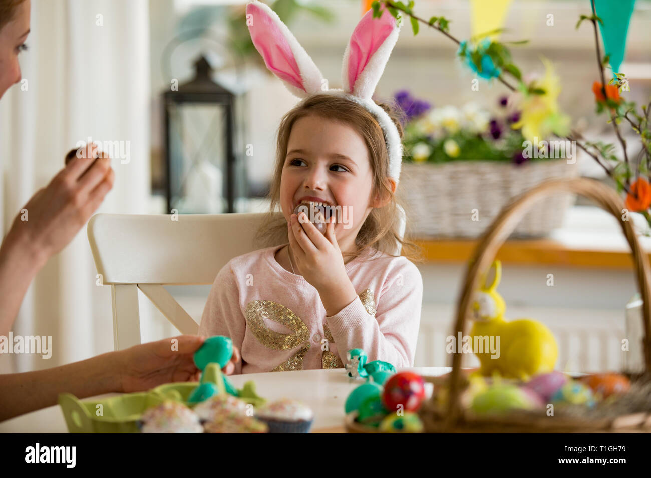 Mother and daughter celebrating Easter, eating chocolate eggs. Happy ...
