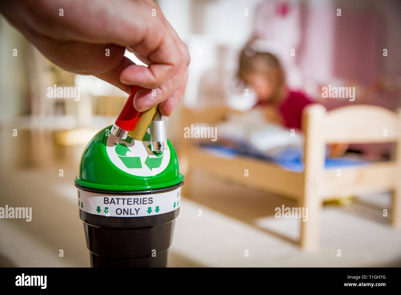 Man putting used batteries into recycling box at home. Child in the ...