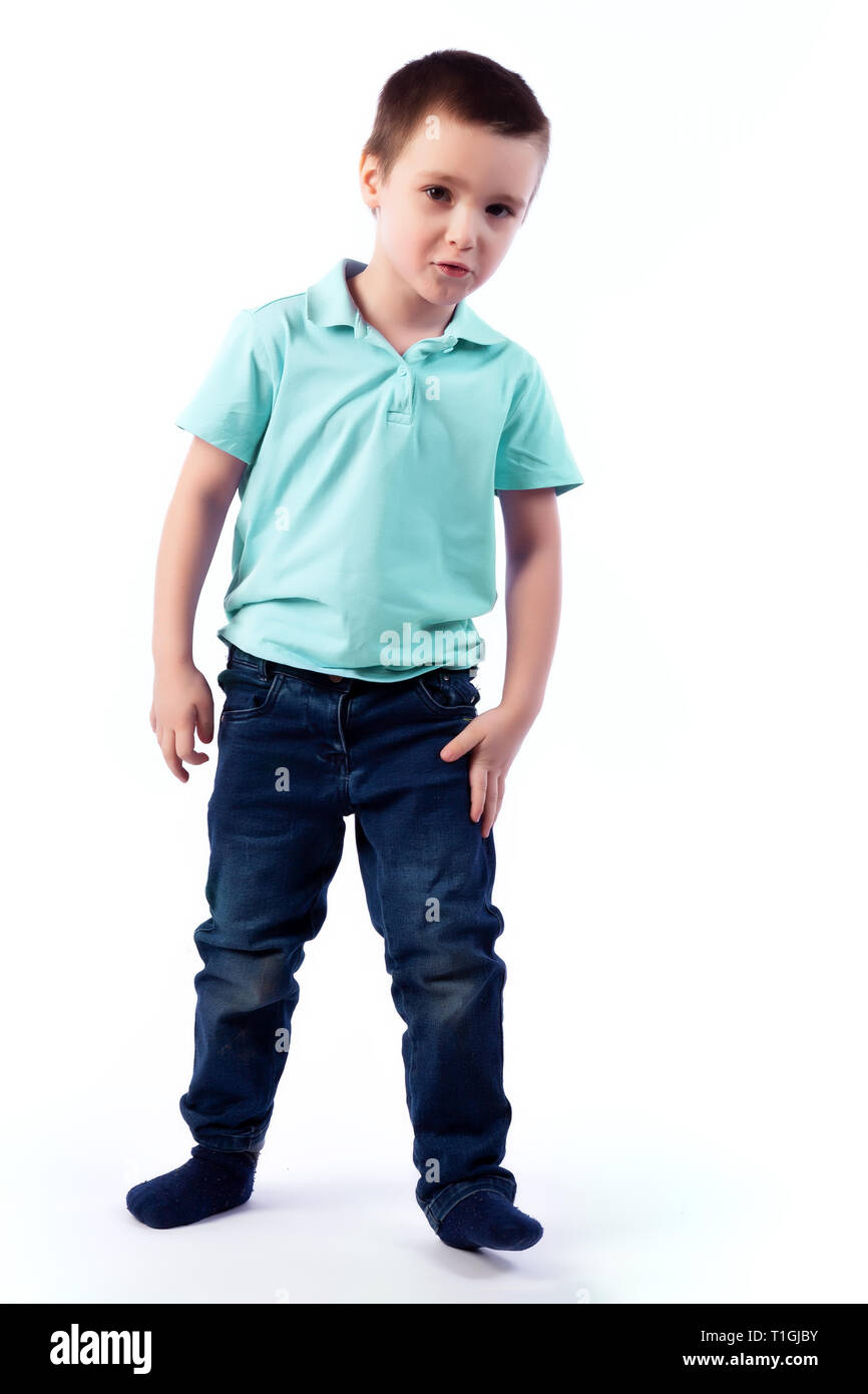 Little smiling boy with dark hair in blue jeans, blue polo t-shirt ...