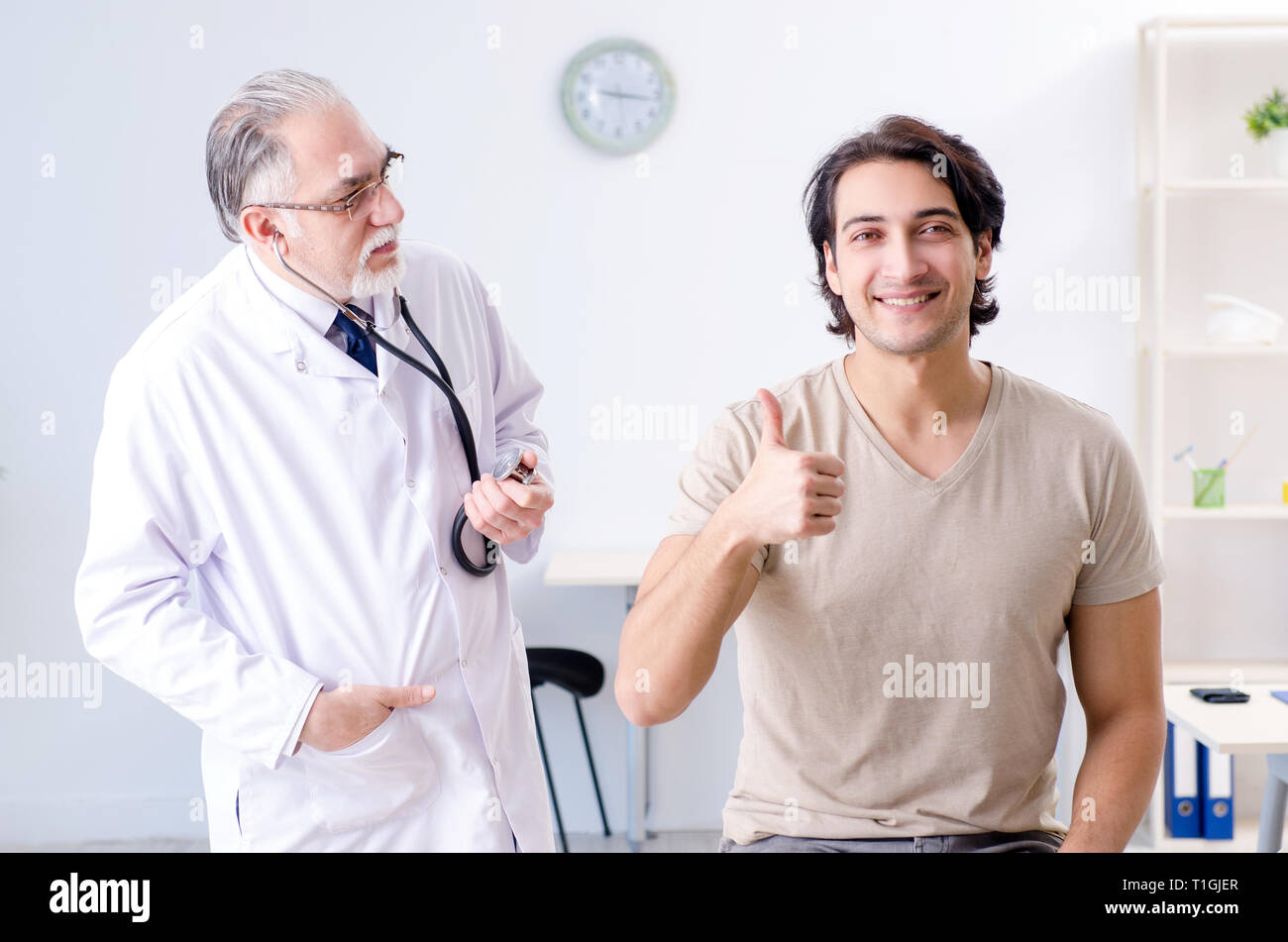 Young male patient visiting old doctor Stock Photo - Alamy