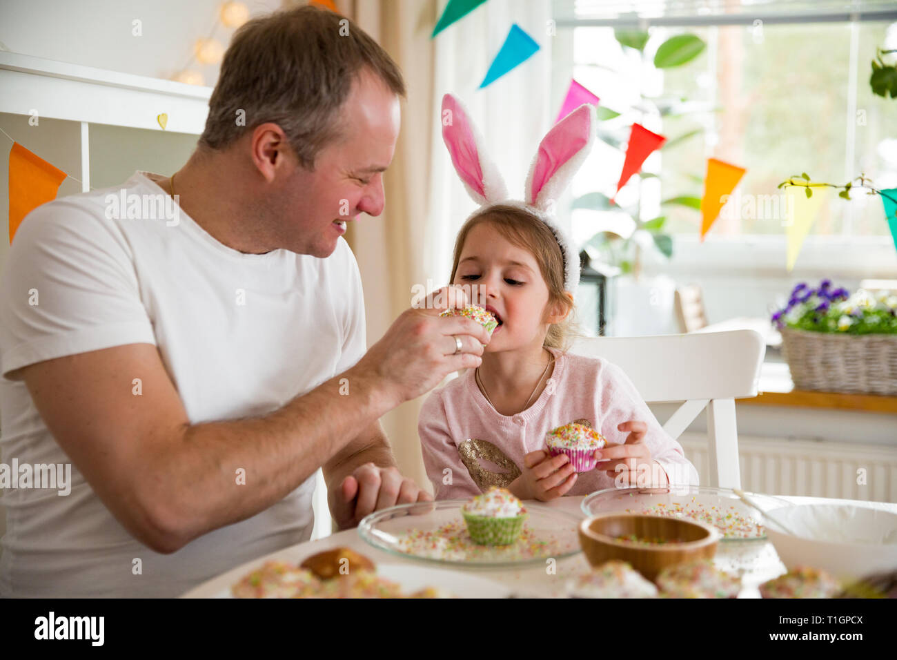 Father and daughter celebrating Easter, eating cupcakes covered with ...