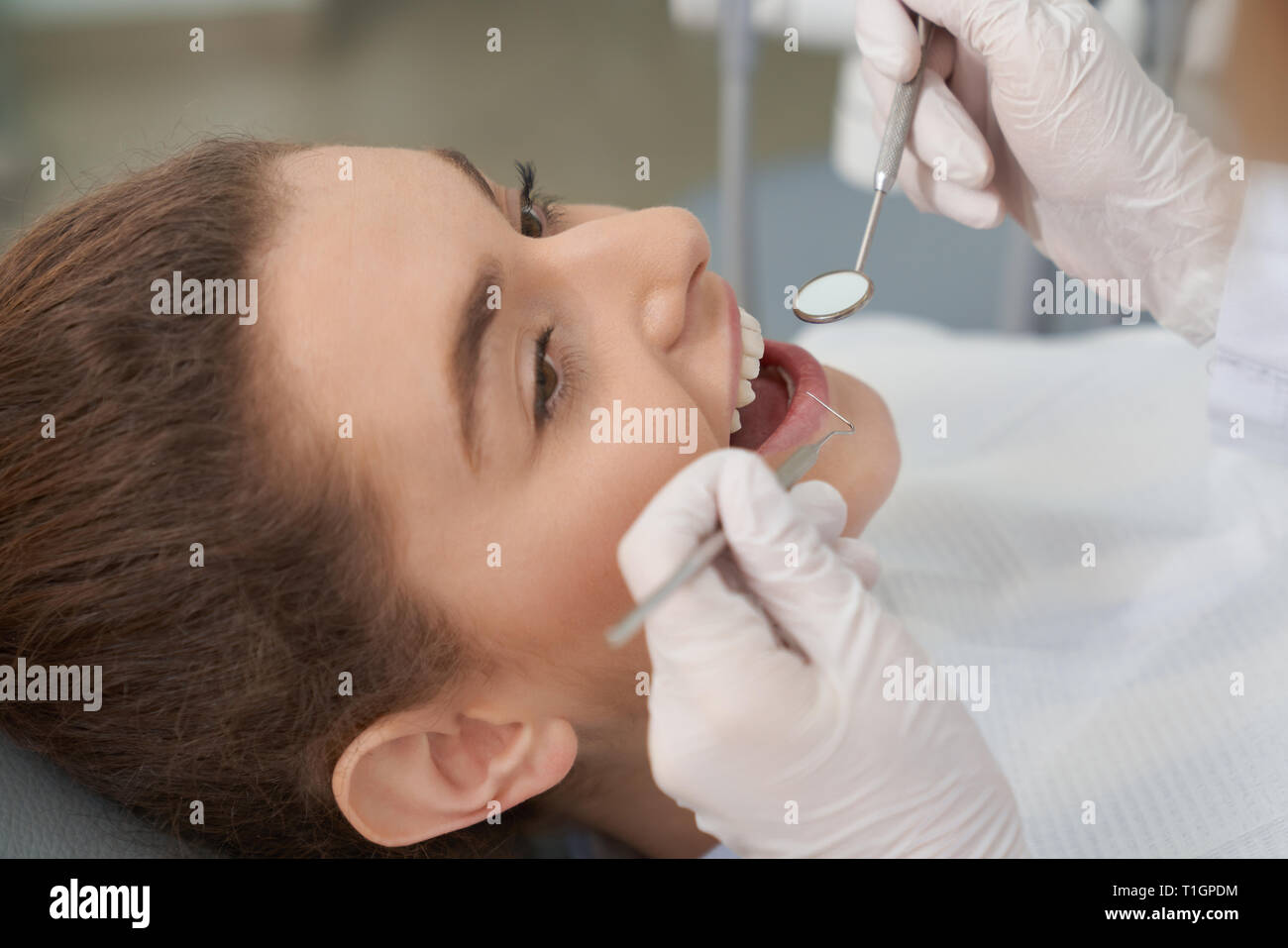 Closeup of pretty young woman lying on dental chair with open mouth and ...