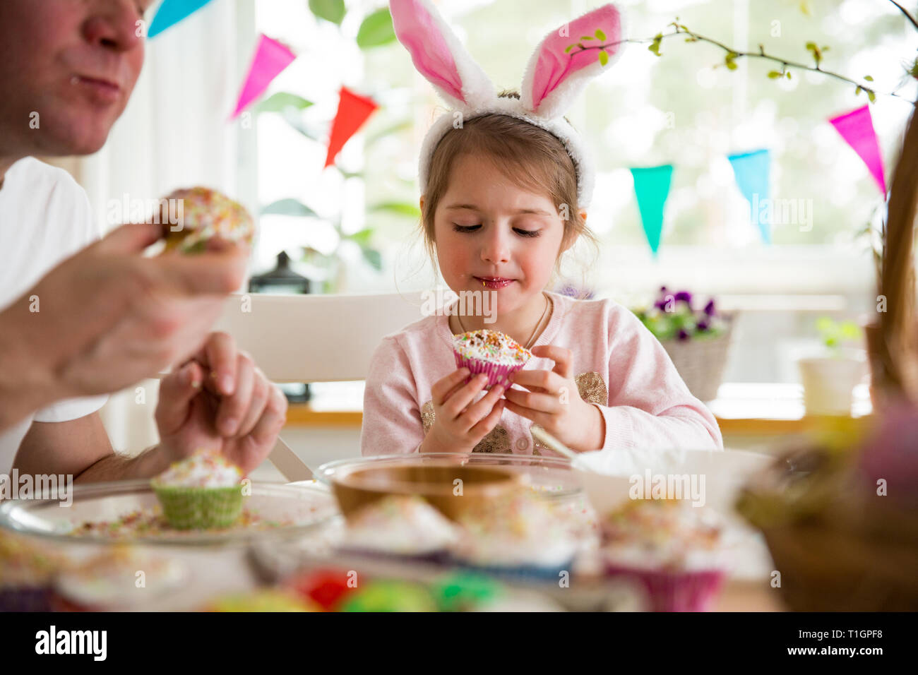 Father and daughter celebrating Easter, eating cupcakes covered with ...