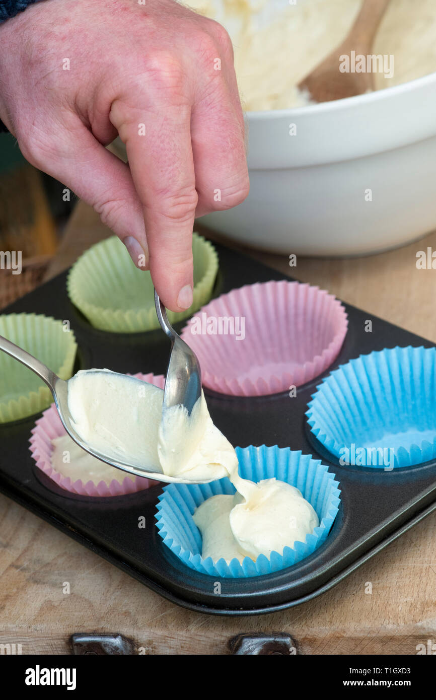 Spooning Vanilla cupcake mixture into cupcake cases. UK Stock Photo - Alamy
