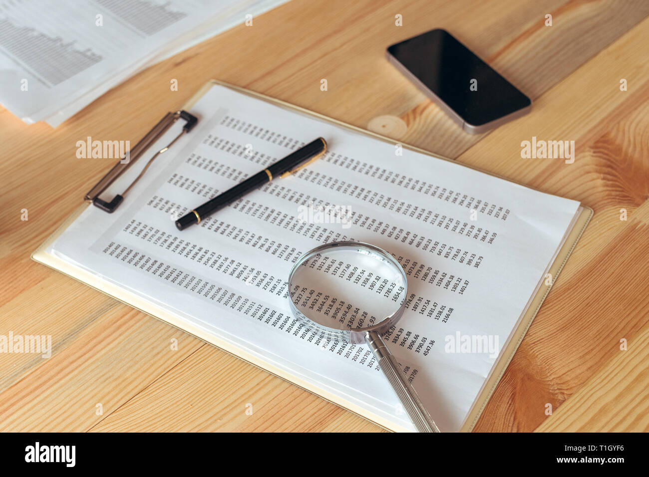 Business report analysis, magnifying glass over paper spreadsheet on ...