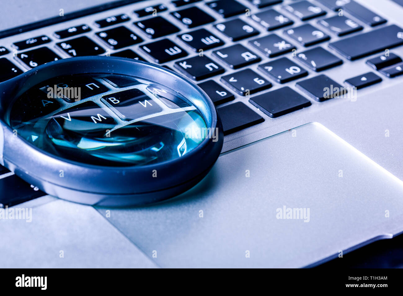 Closeup images of magnifying glass on laptop keyboard Stock Photo - Alamy