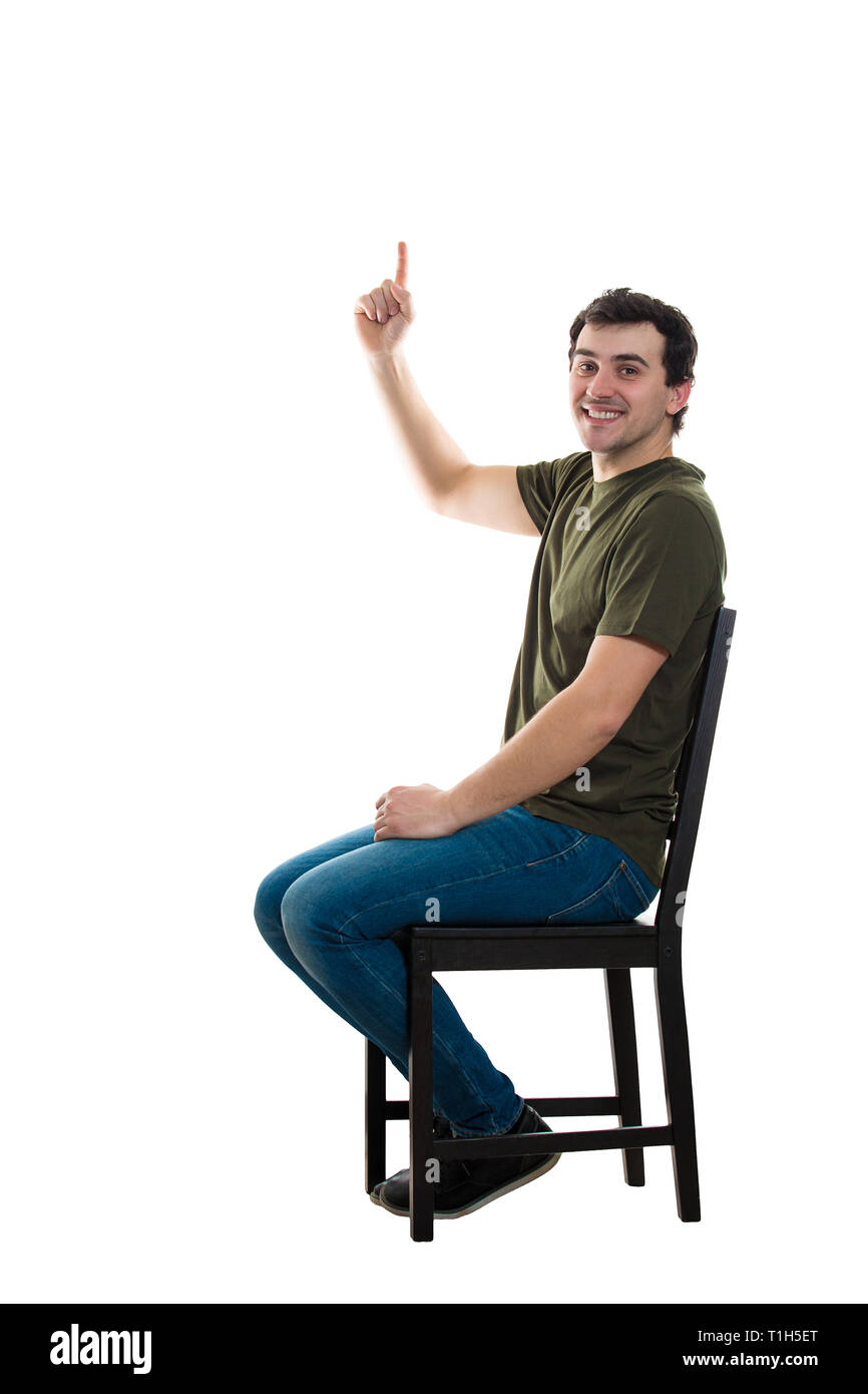 Side view full length portrait of casual young man seated on a chair ...