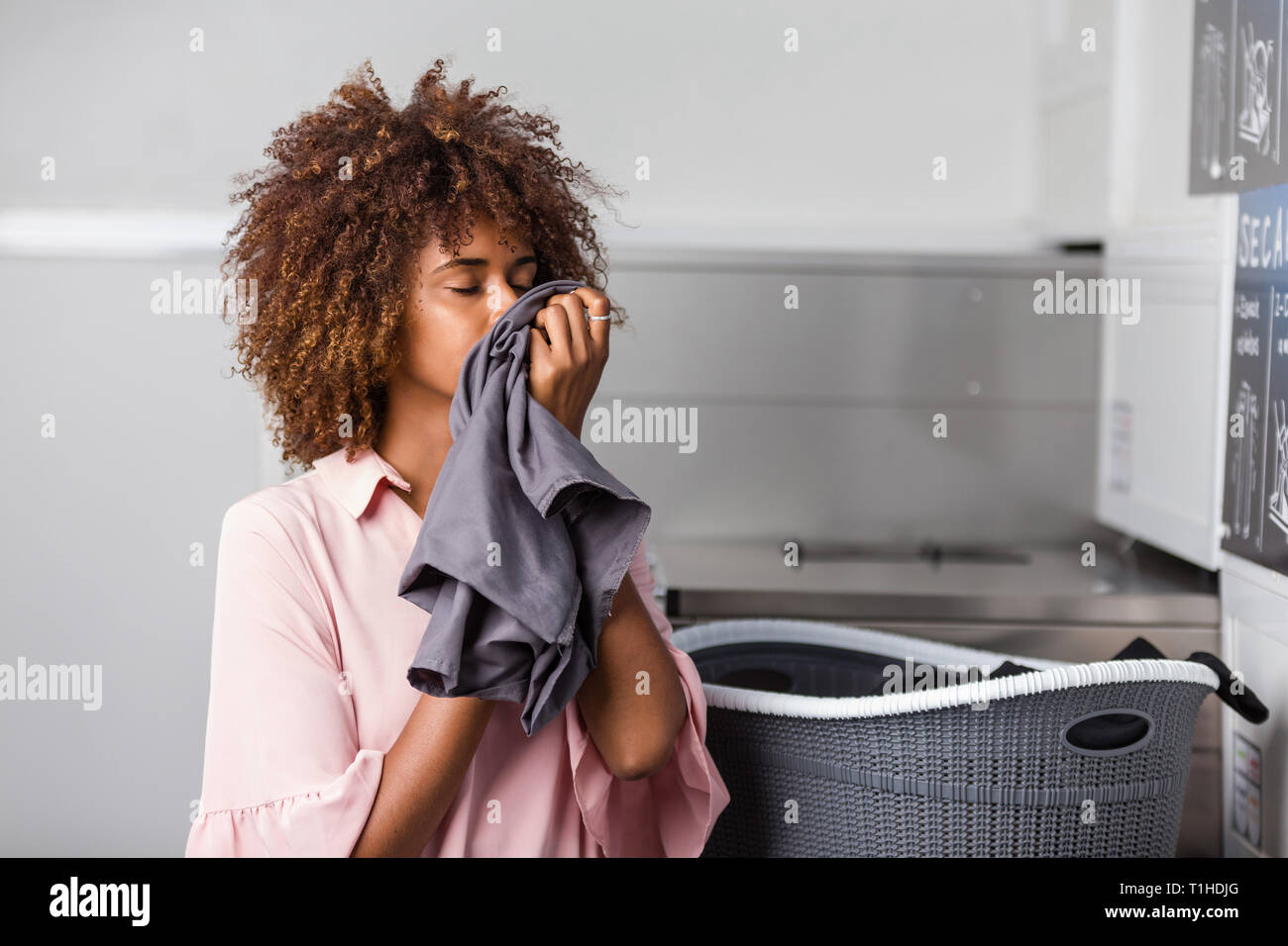 Young black African American woman washing her clothes in a automatic ...