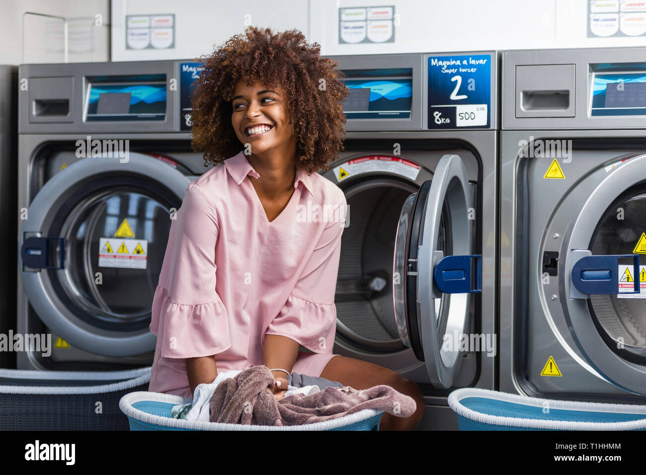 Young black African American woman washing her clothes in a automatic ...