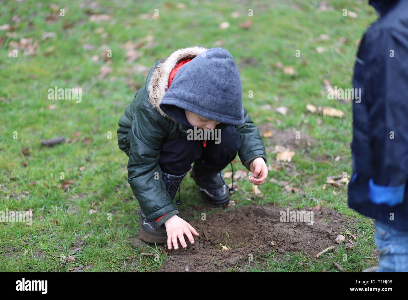 A boy crouching looking at the ground Stock Photo - Alamy