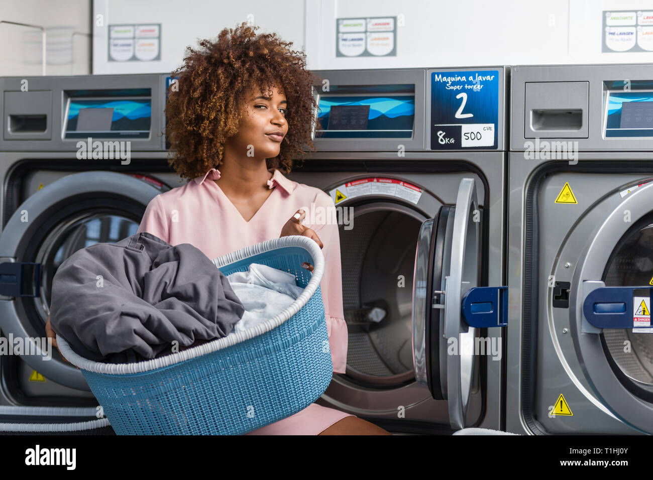 Young black African American woman washing her clothes in a automatic ...