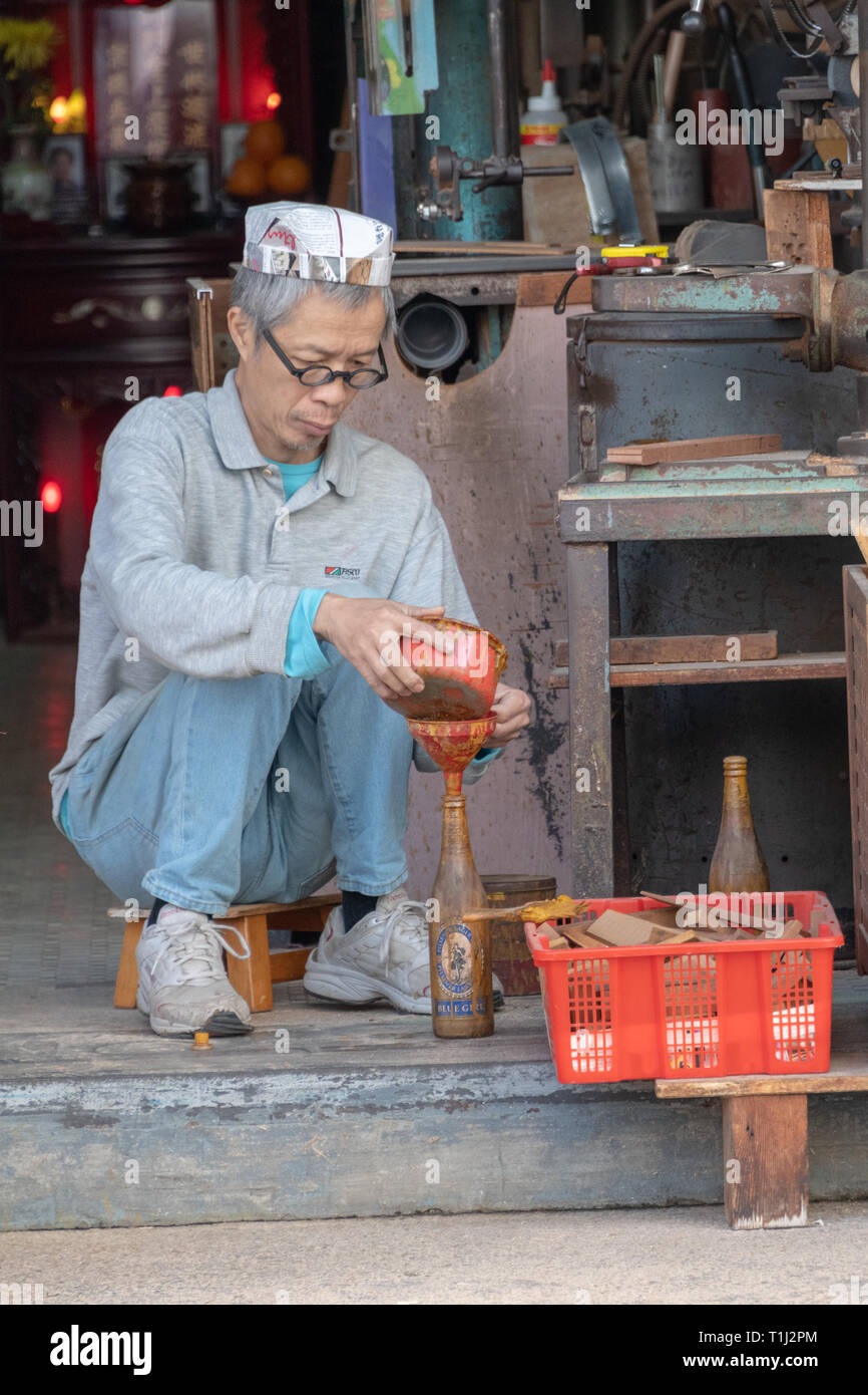 Man Sitting on Stool in Shop Pouring Oil in Funnel Stock Photo - Alamy