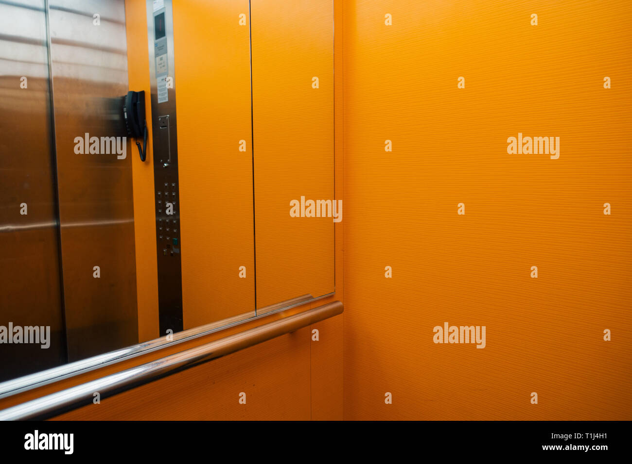 The bright orange 1970s style interior of a Soviet-era elevator in the ...