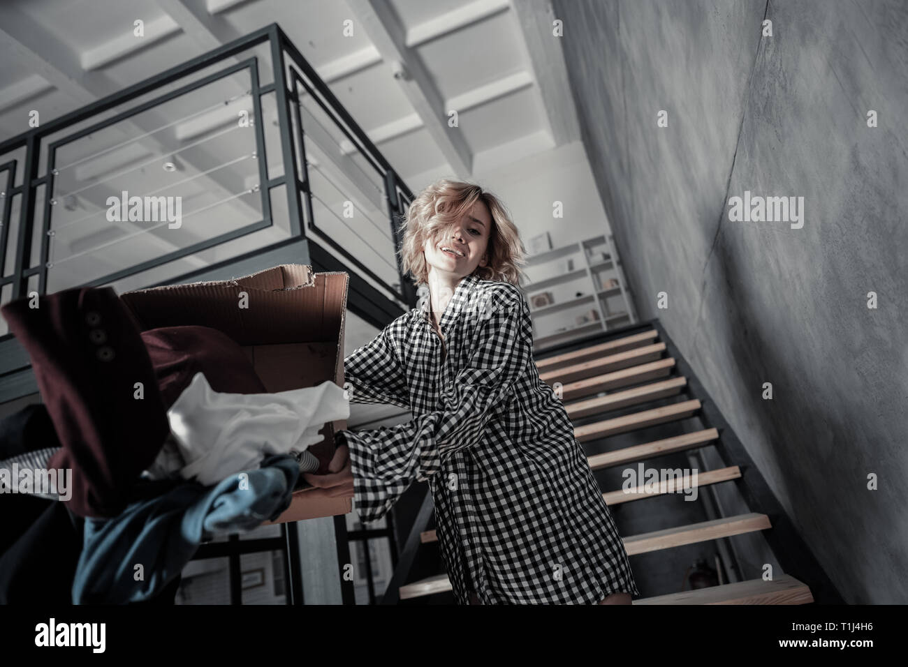 Woman wearing squared shirt throwing box with clothes away Stock Photo ...