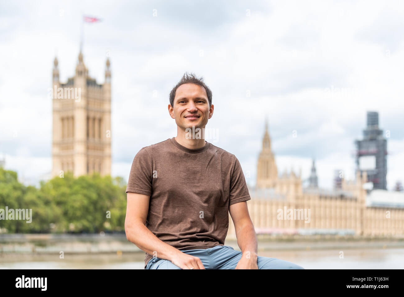 London, UK happy smiling man face sitting on railing by cityscape ...