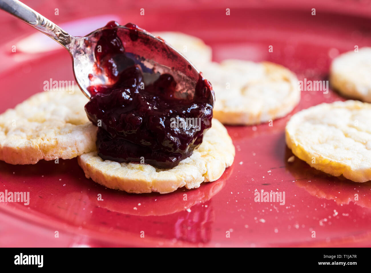 Eating plum jam on a red plate with corn / rice biscuits Stock Photo ...