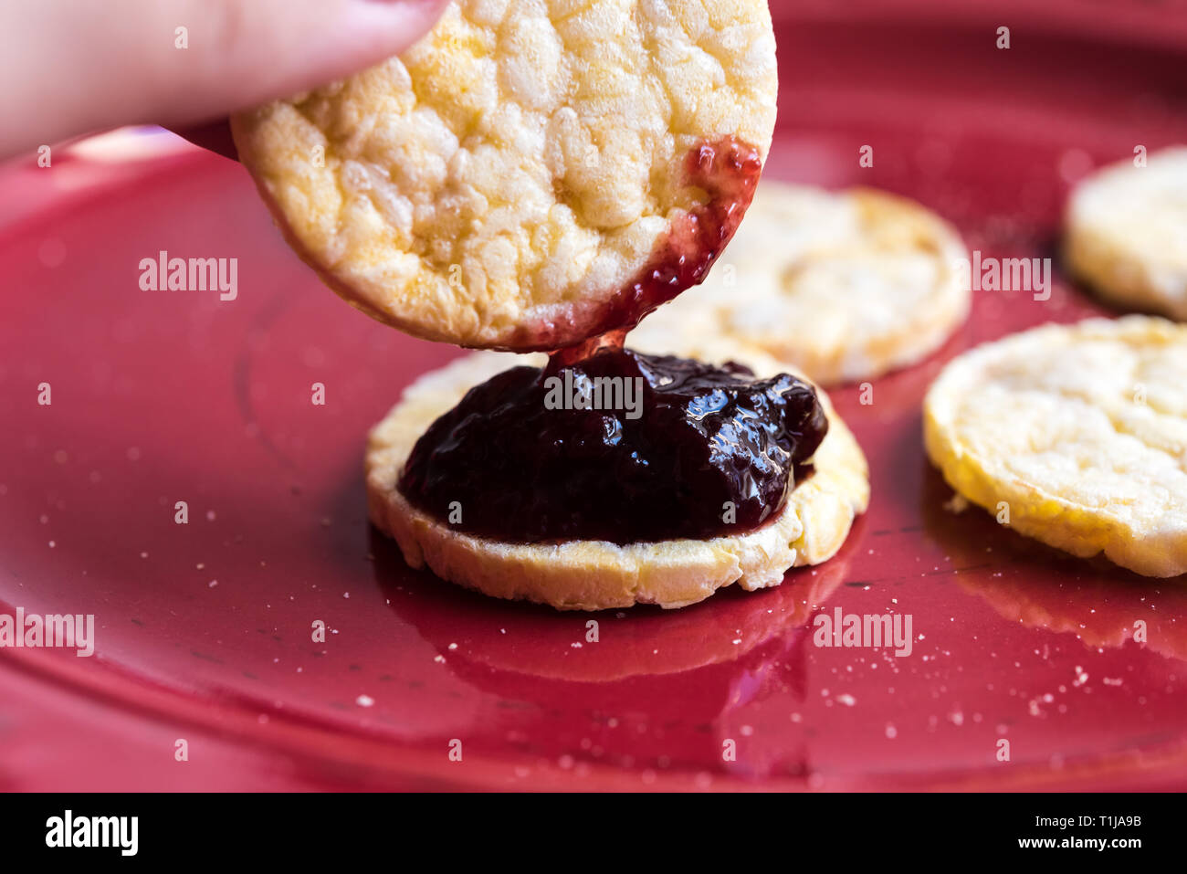 Eating plum jam on a red plate with corn / rice biscuits Stock Photo ...
