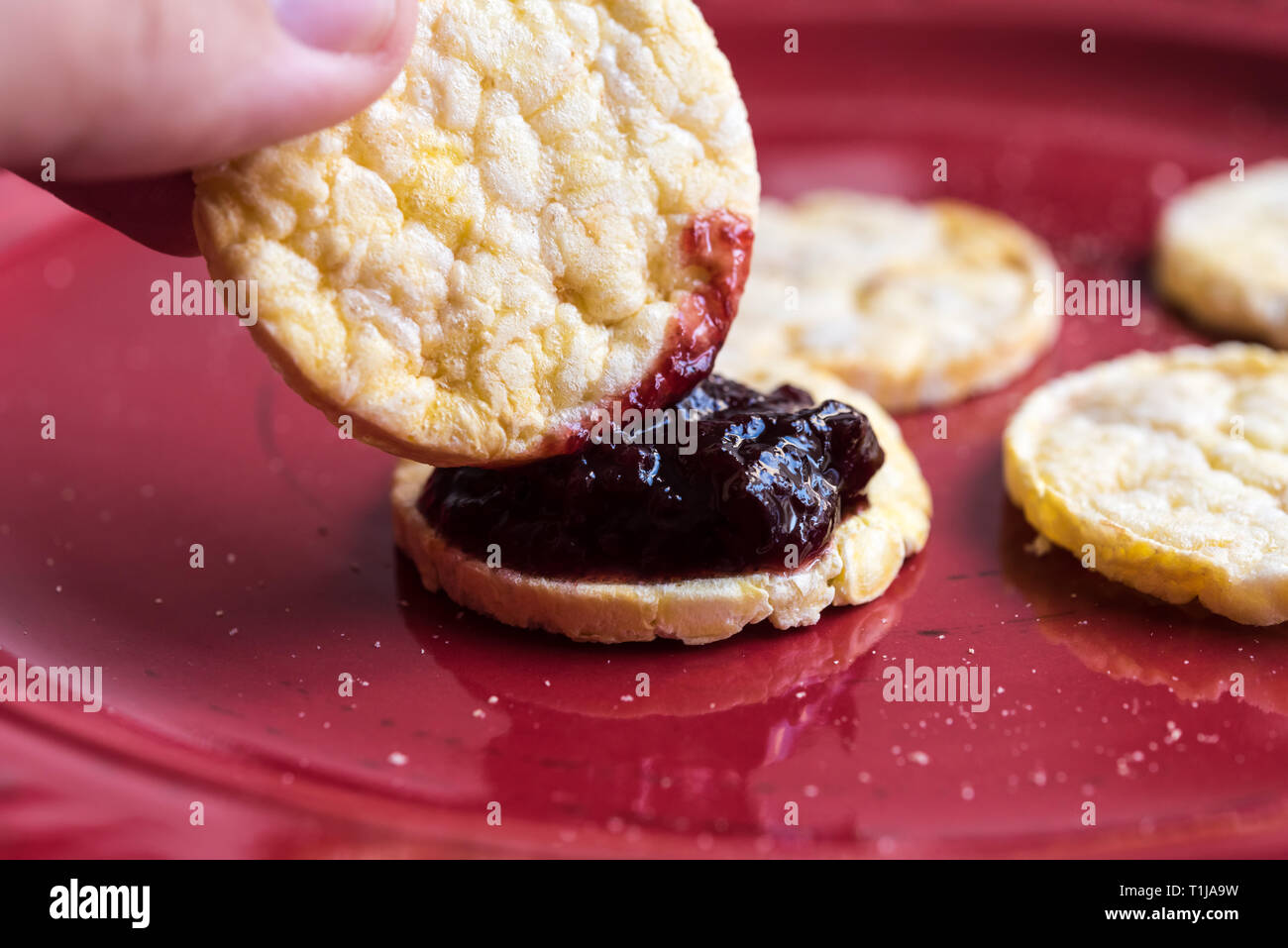 Eating plum jam on a red plate with corn / rice biscuits Stock Photo ...