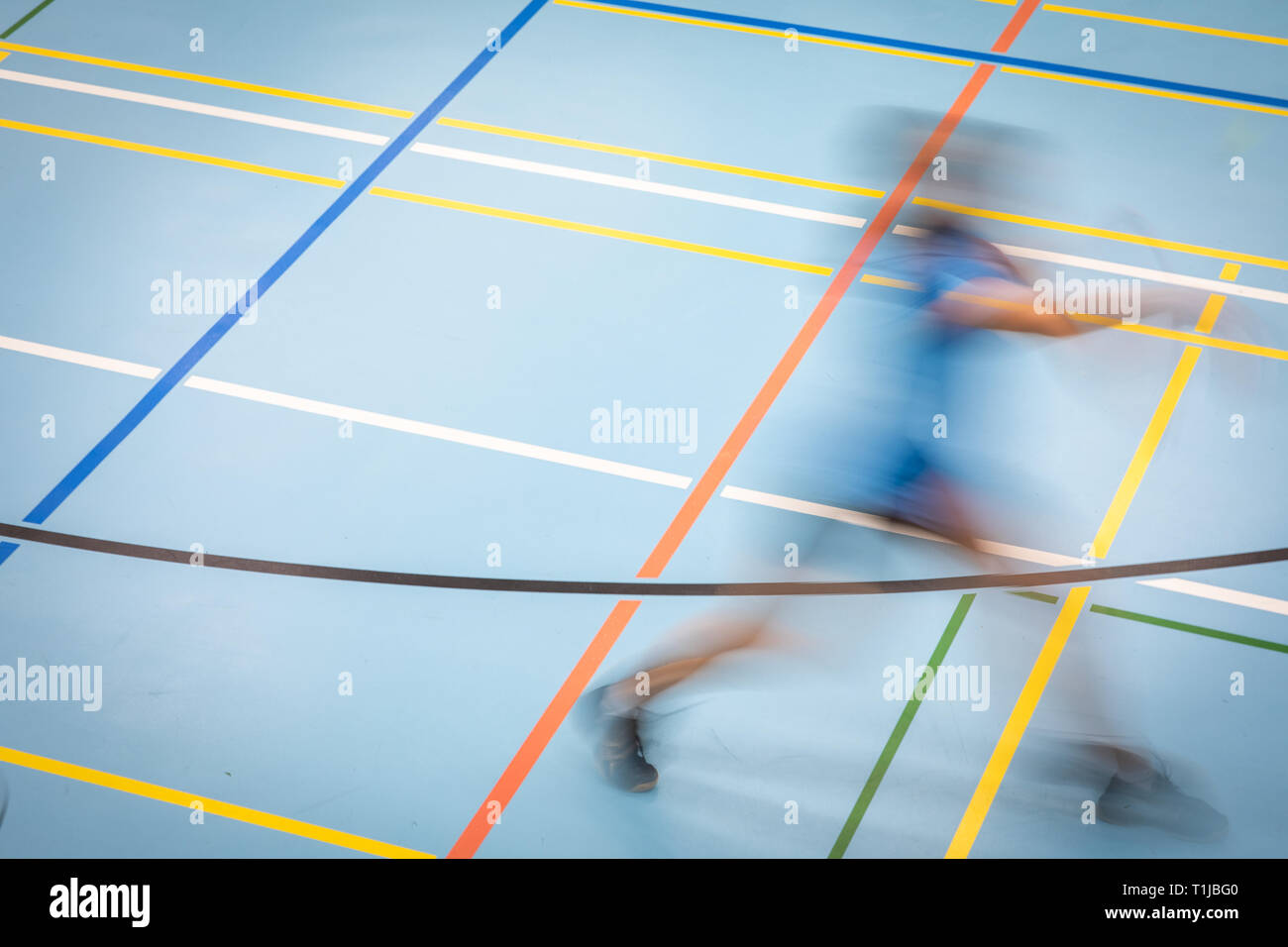 Badminton player in fast motion on a badminton court in a gymnasium ...