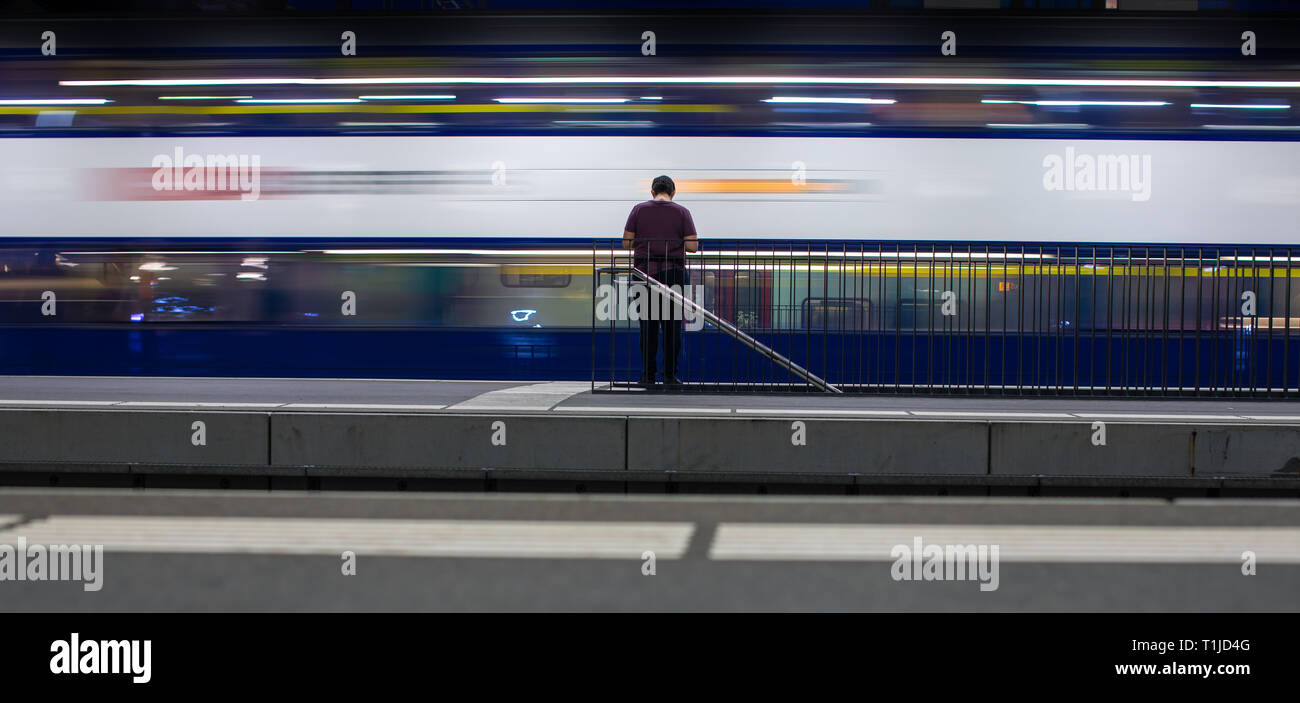 People in a trainstation with motion blurred trains moving fast (color ...